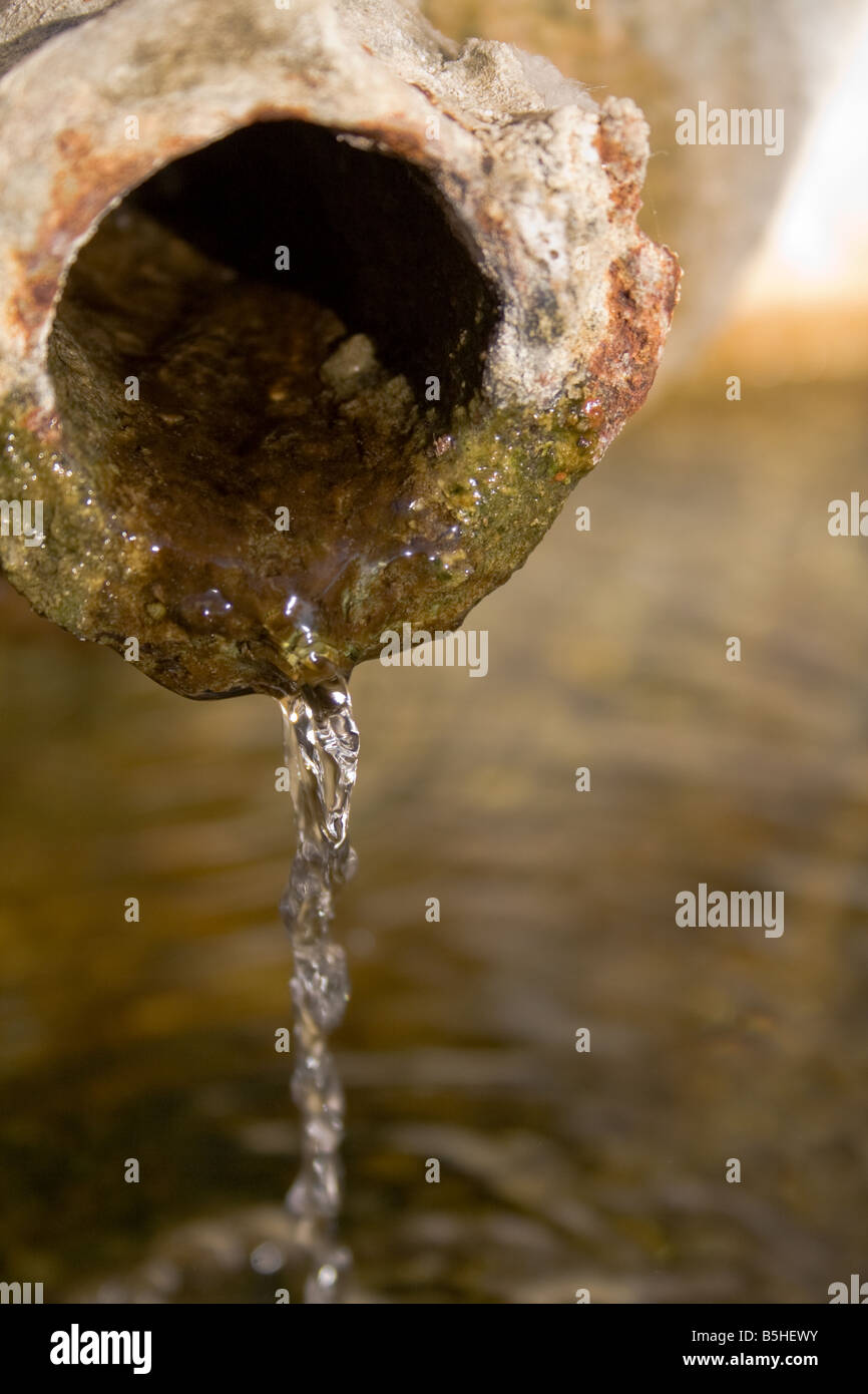 Thin string of water pouring from an old fountain pipe Stock Photo - Alamy