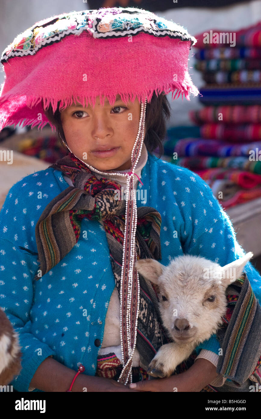 a young Peruvian girl is dressed in traditional attire and holding a ...