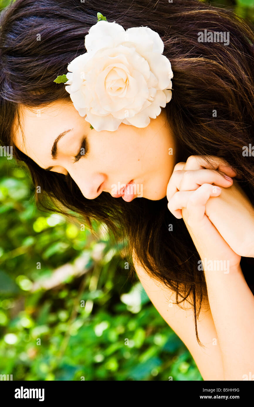 Young woman praying with a white rose in her hair Stock Photo - Alamy
