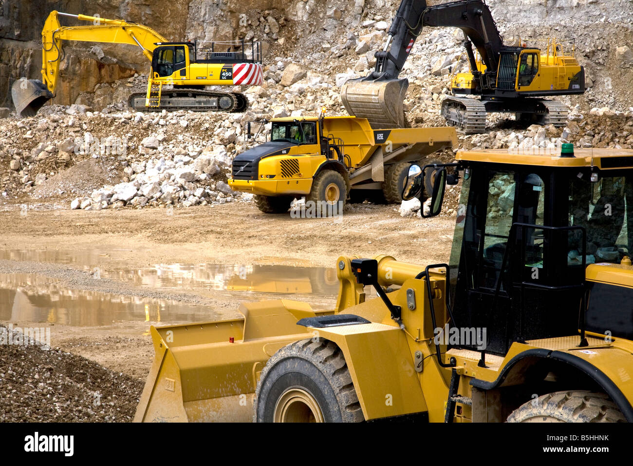 Scene in a busy quarry showing diggers, excavators, dumpers and ...