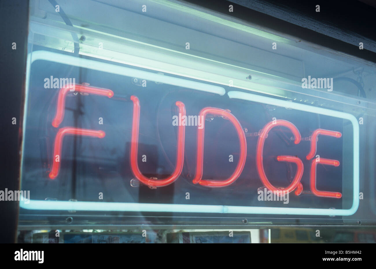 Lit neon sign set in perspex box hanging in shop window stating in red ...