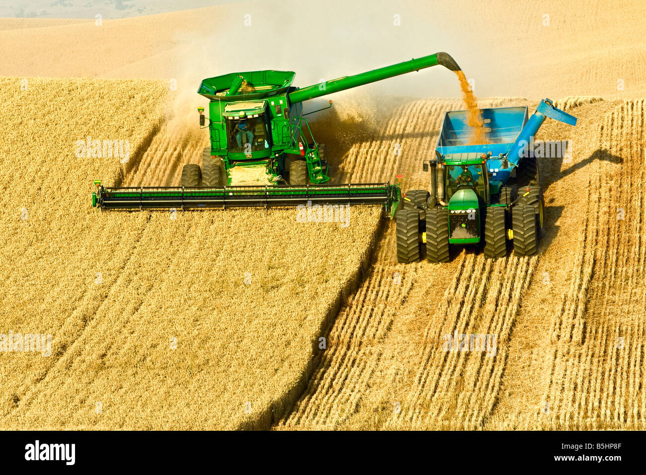 A combine unloads into a grain cart on the go in the Palouse region of ...