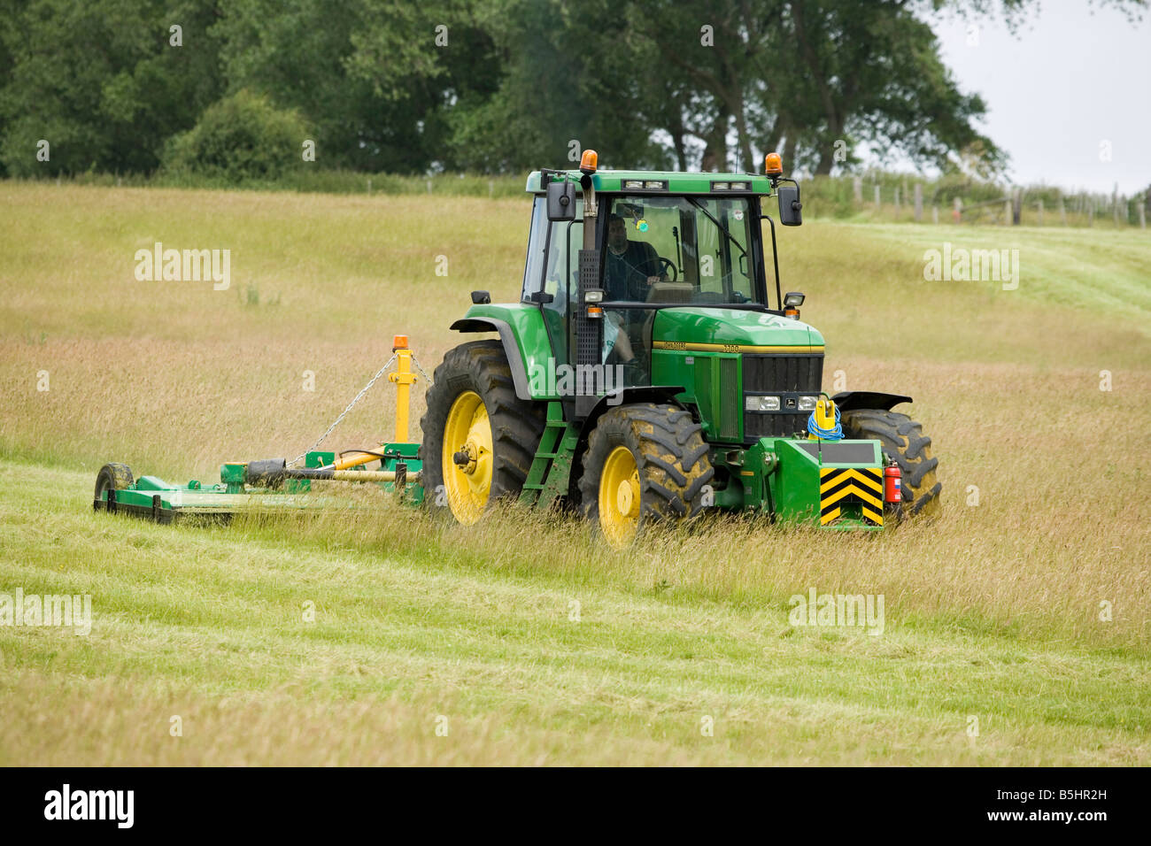 Farmer mowing field of grass using John Deere tractor Stock Photo - Alamy