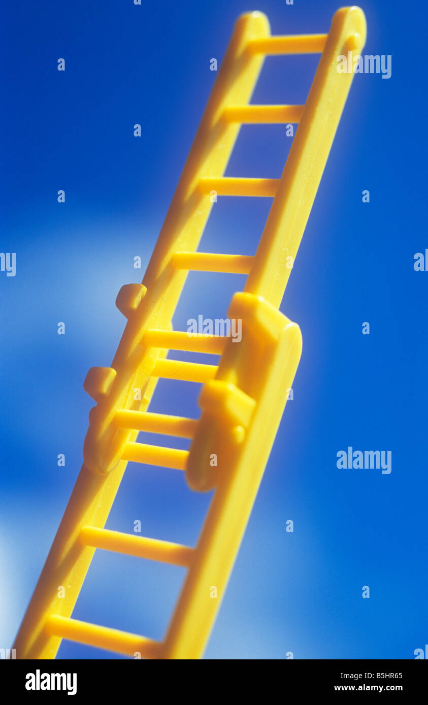 Close up of bright yellow plastic ladder reaching up into blue sky with ...