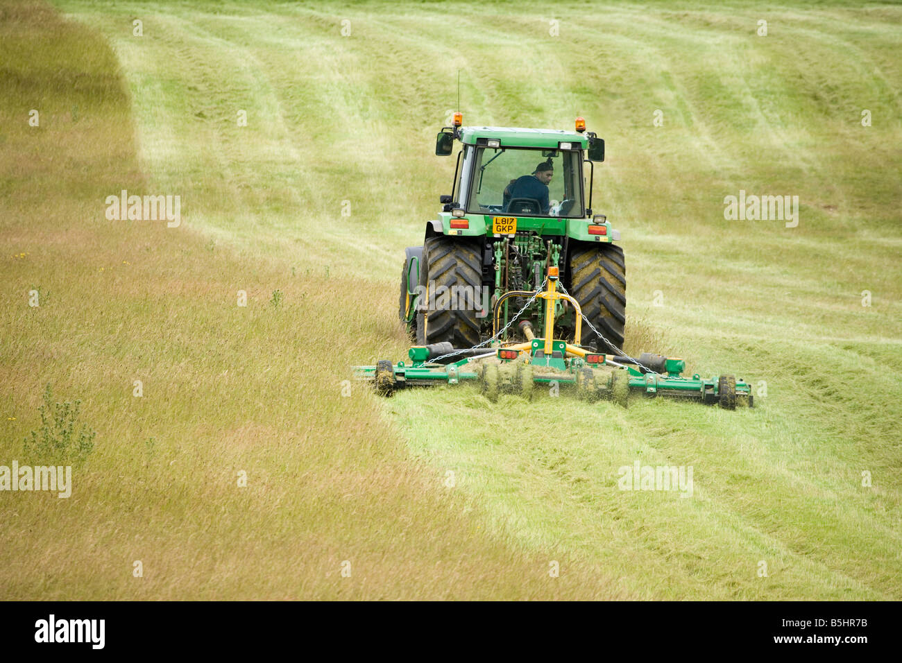 Farmer mowing field of grass using John Deere tractor Stock Photo - Alamy