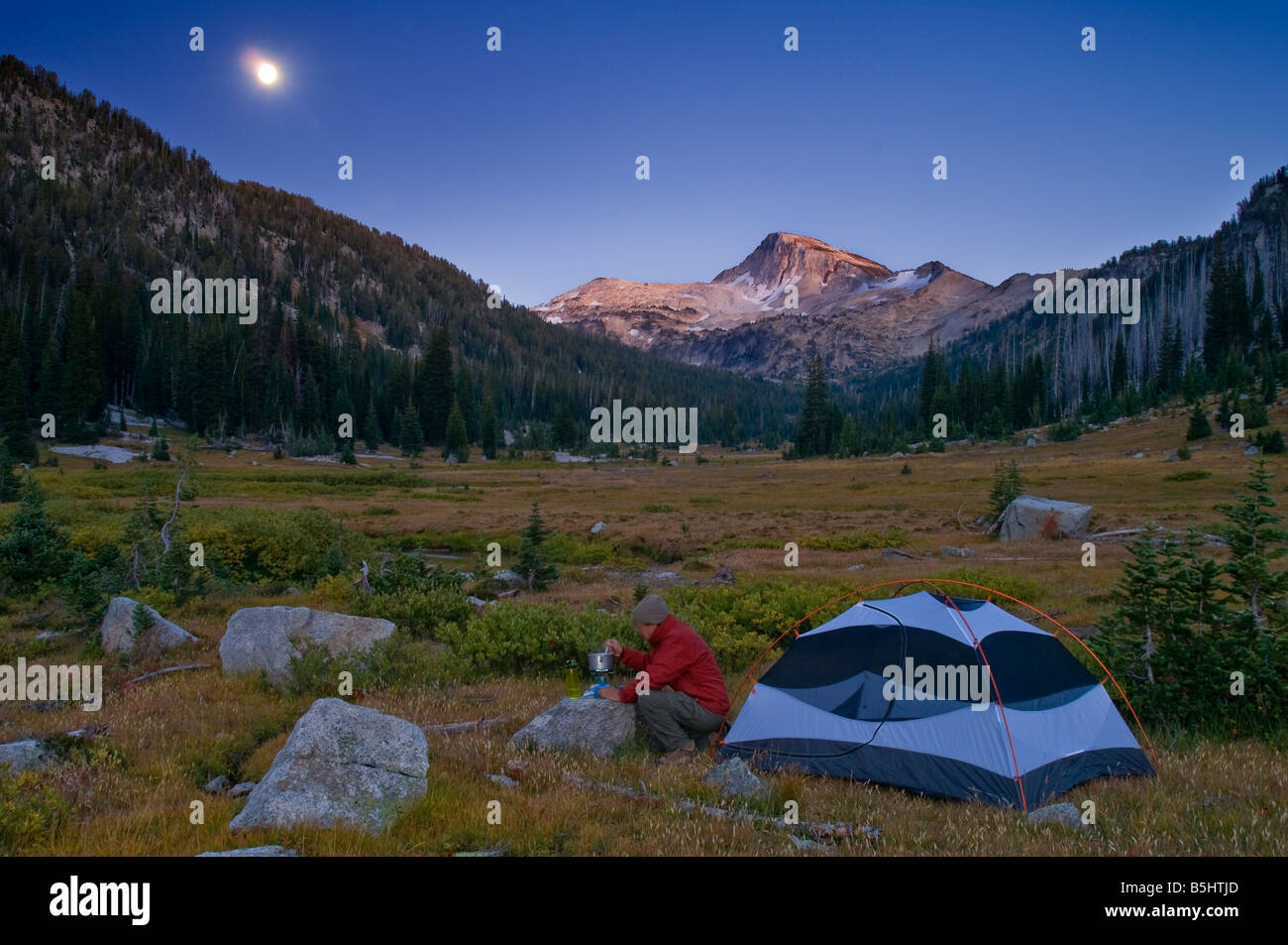Backpacking camper Lostine River valley meadow moon rise over Eagle Cap ...
