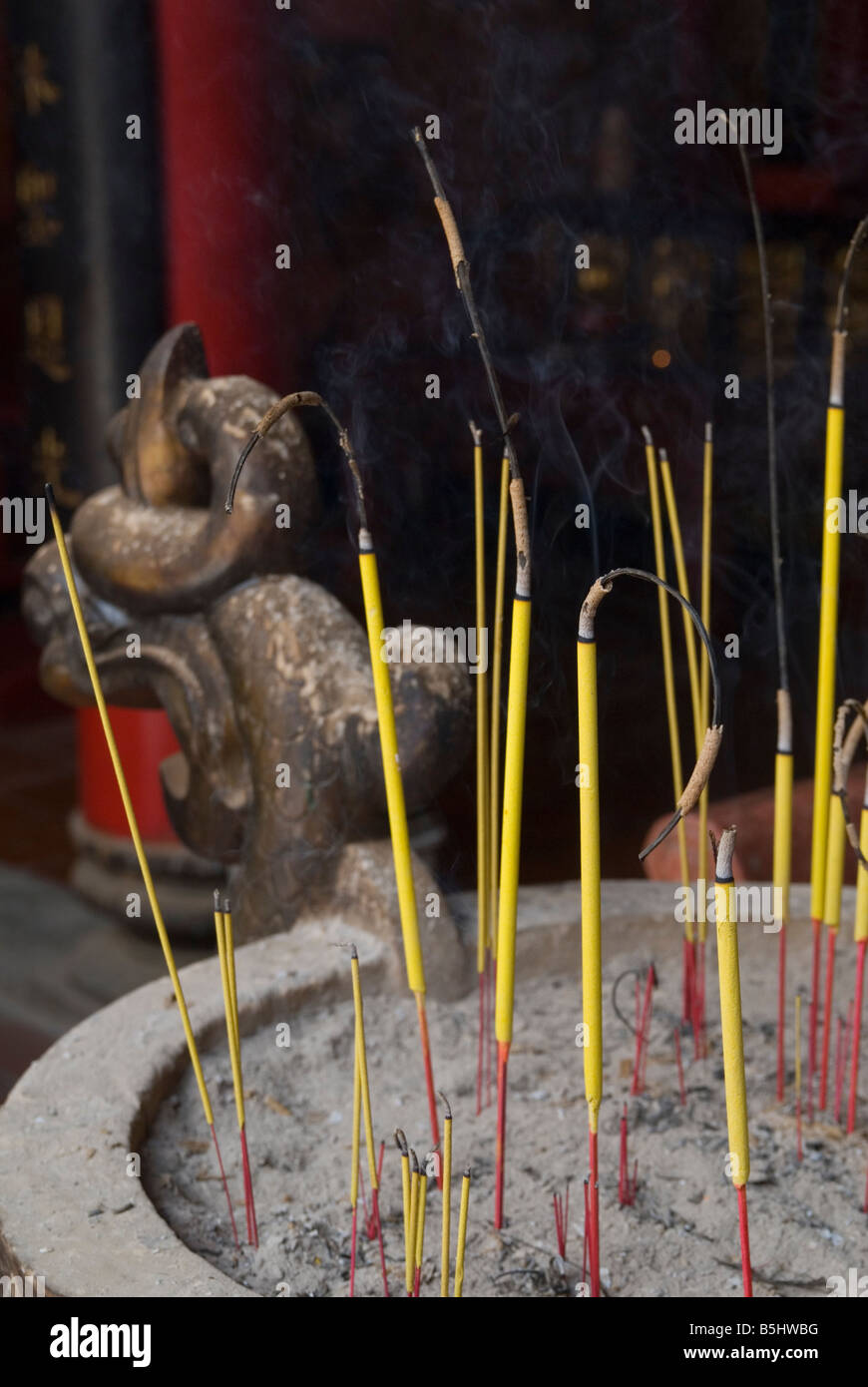 Yellow and red joss sticks stand in sand at the Ha Chuong Hoi Quan ...