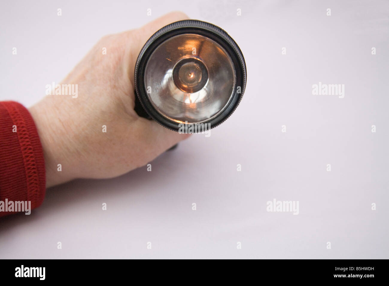 Studio Close up of a hand working a black dynamo driven wind up torch ...