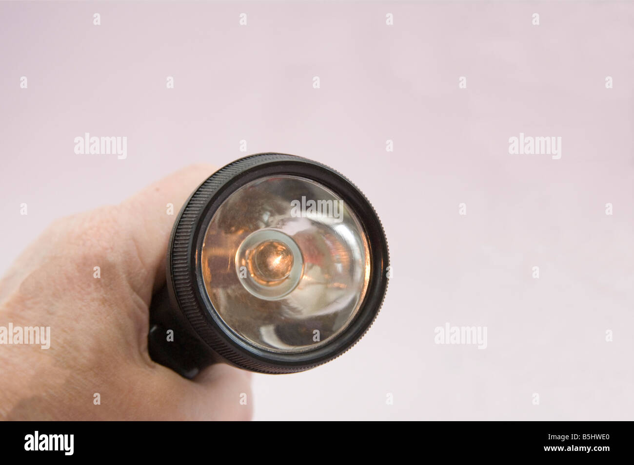 Studio Close up of a hand working a black dynamo driven wind up torch ...