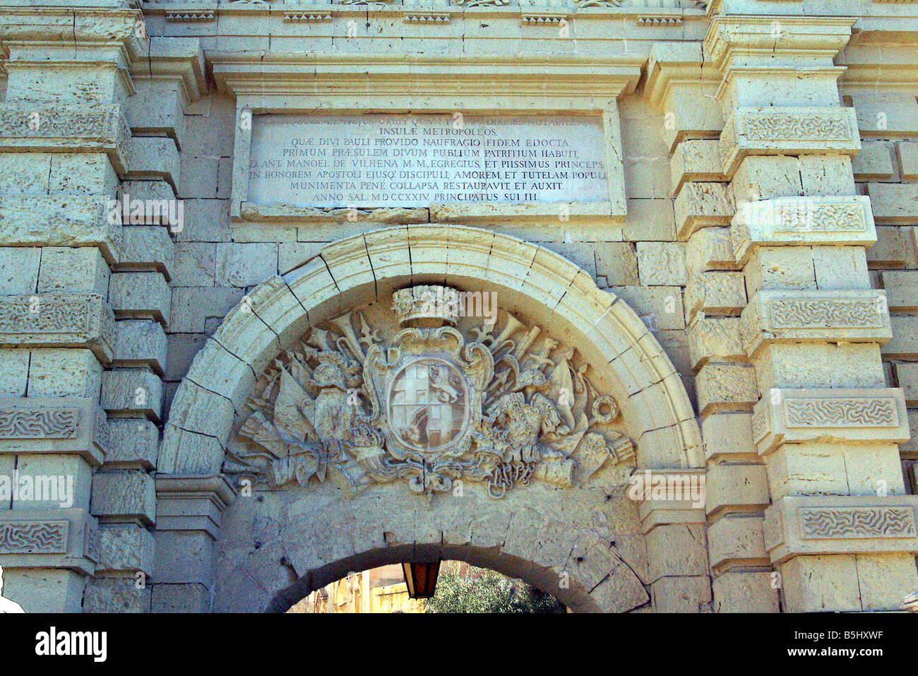 A sculpted coat of arms and inscription above the arched gateway to the ...
