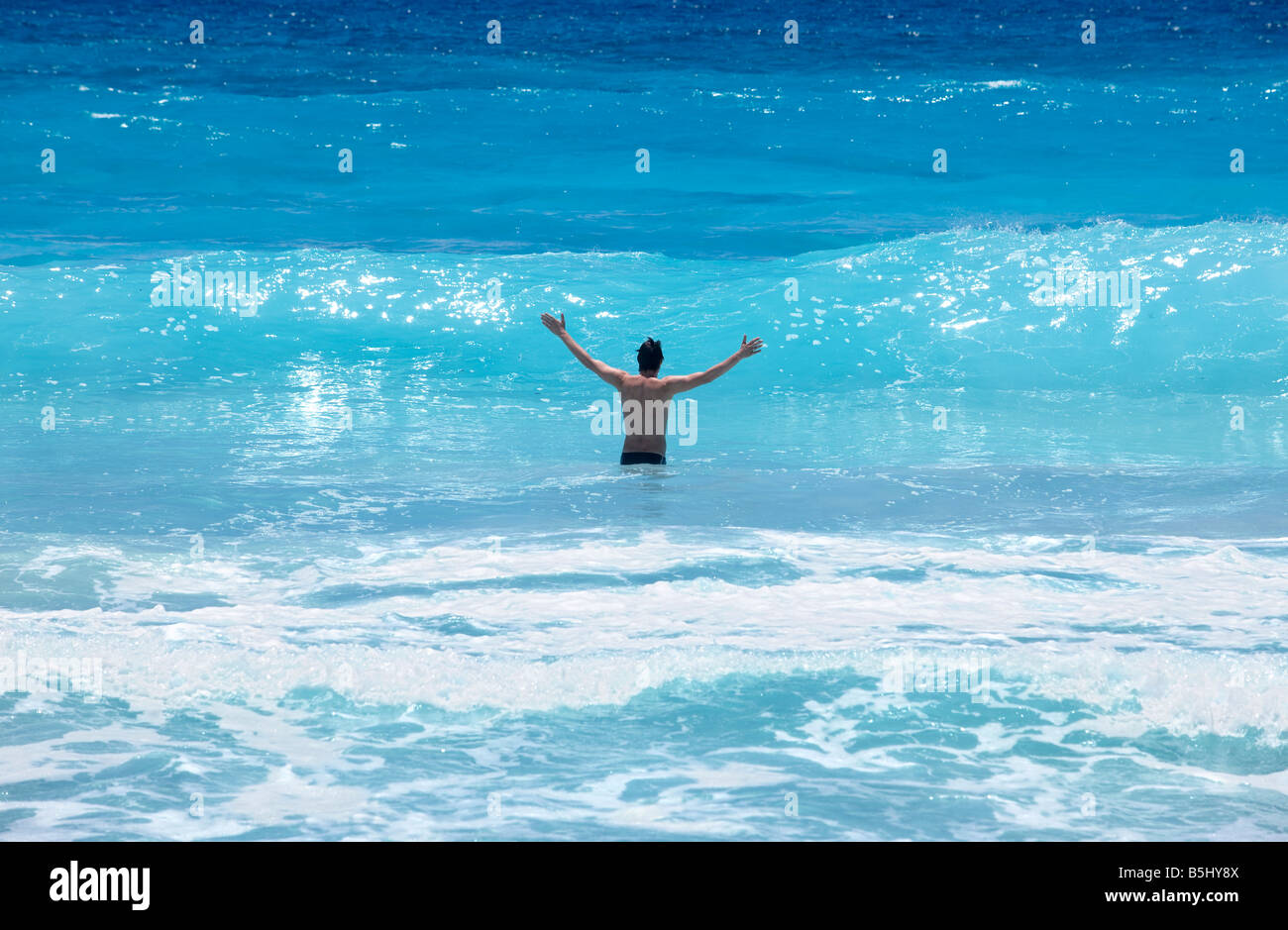 man facing wave in grand anse La Digue Island Seychelles Stock Photo ...