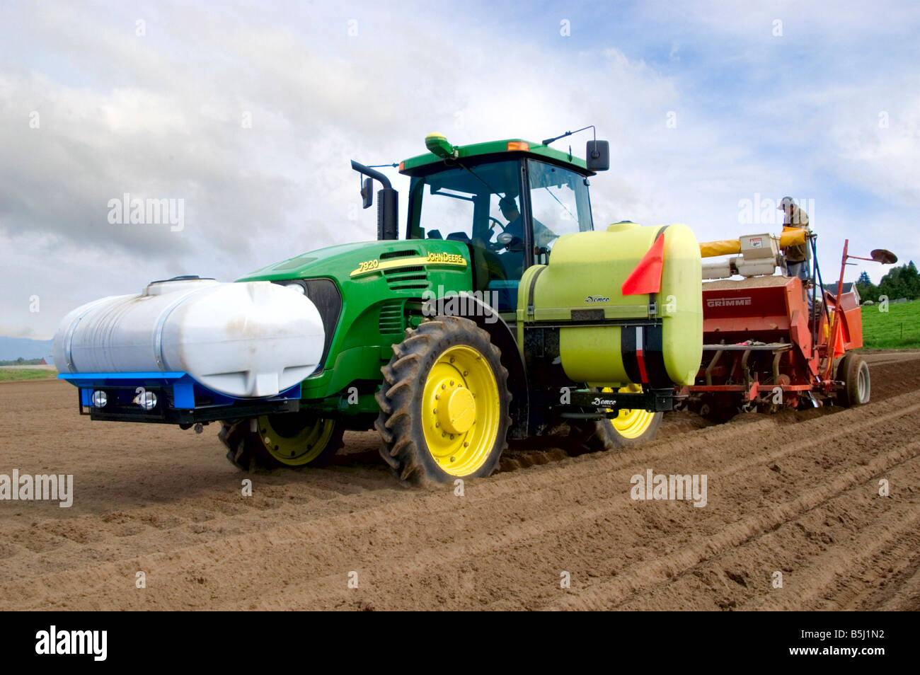 A gps guided tractor pulls a 4 row potato planter during spring ...