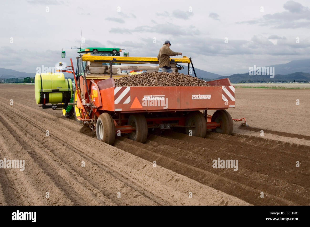 A gps guided tractor pulls a 4 row potato planter during spring ...