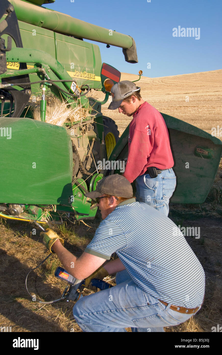 A pair of combine operators perform maintenance on combine in the ...