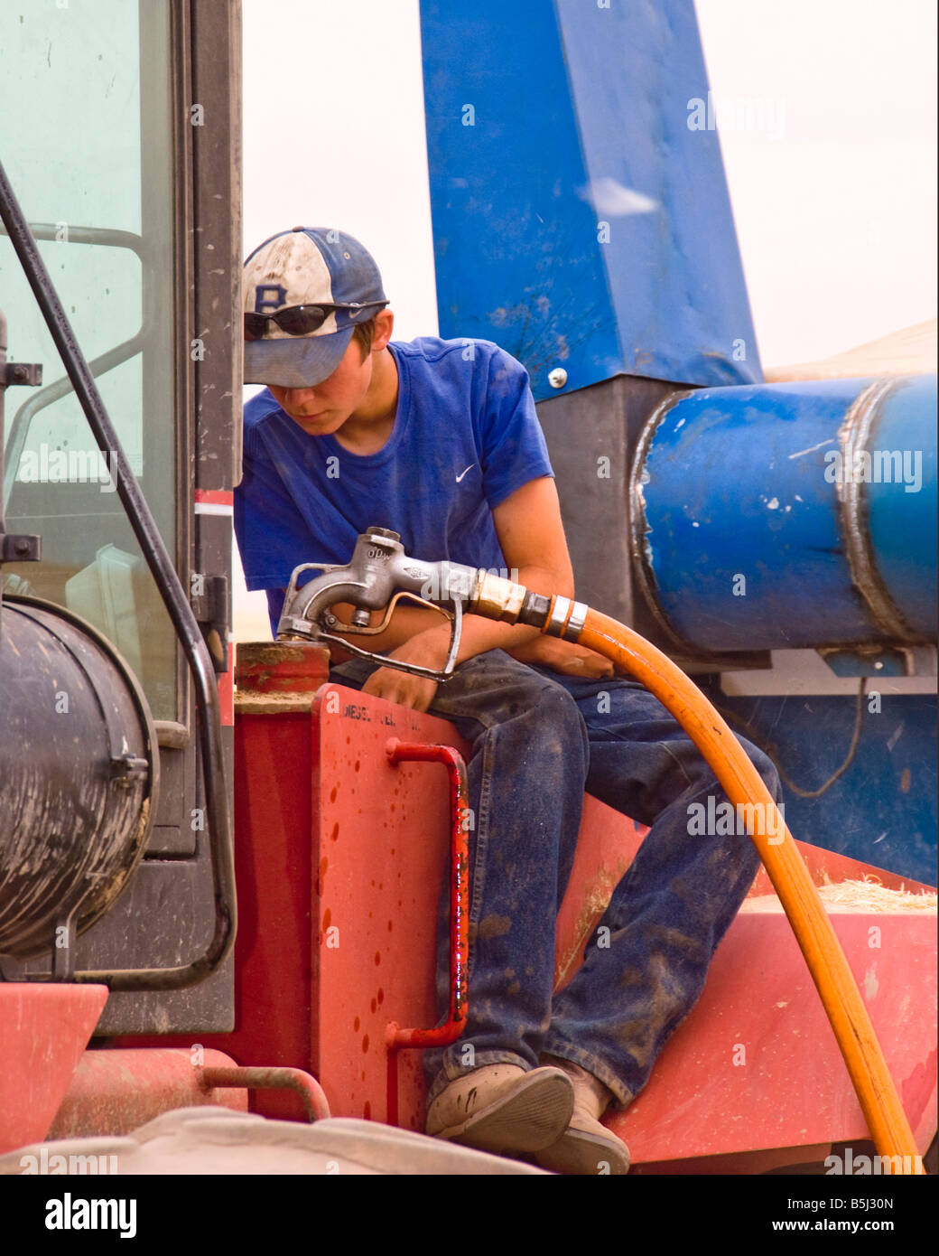 A tractor operator fuels his tractor prior to beginning harvest ...