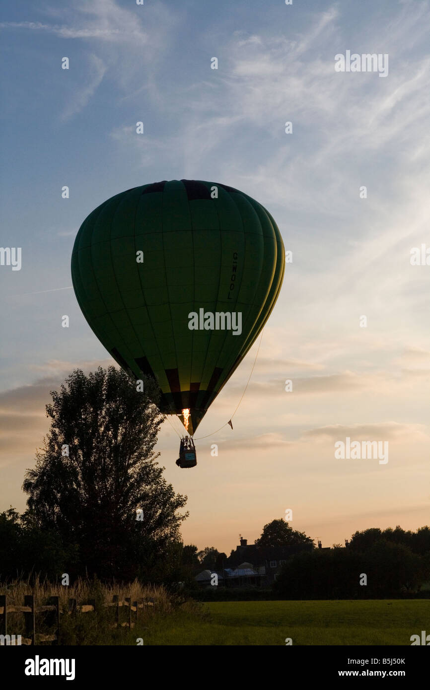 Hot air balloon landing in a field at sunset Stock Photo - Alamy