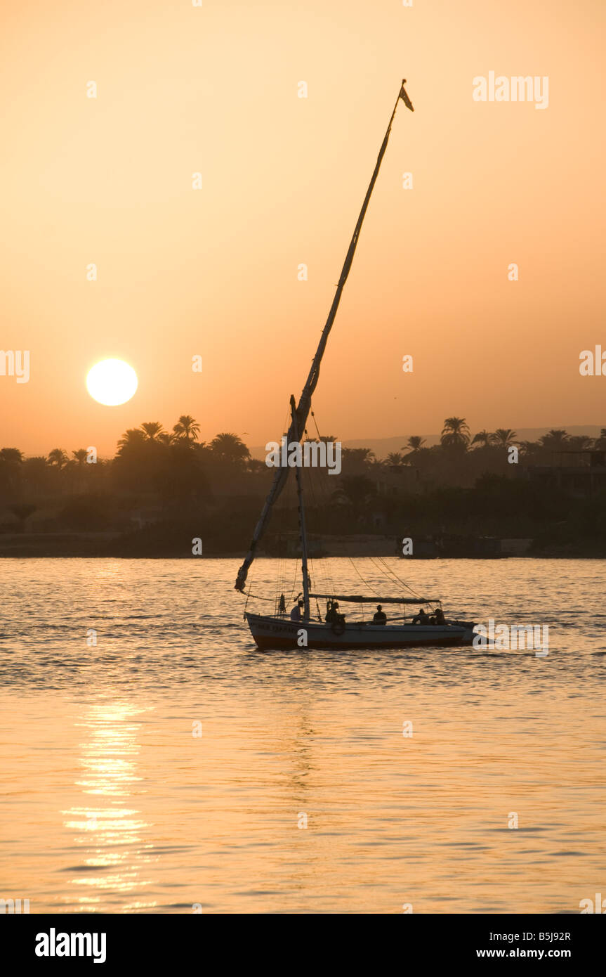 A silhouetted felucca traditional wooden sailing boat on the Nile river ...