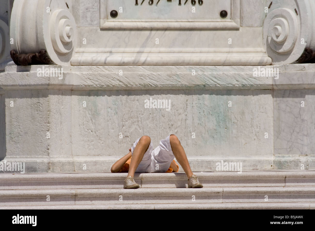 A man lying by the pedestal of a statue Stock Photo - Alamy