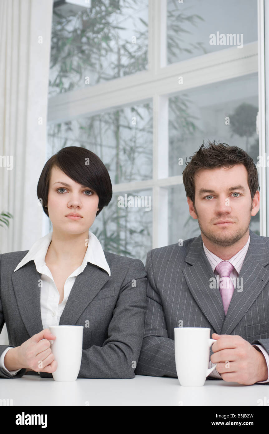 portrait of two business people sitting at table with cups Stock Photo ...
