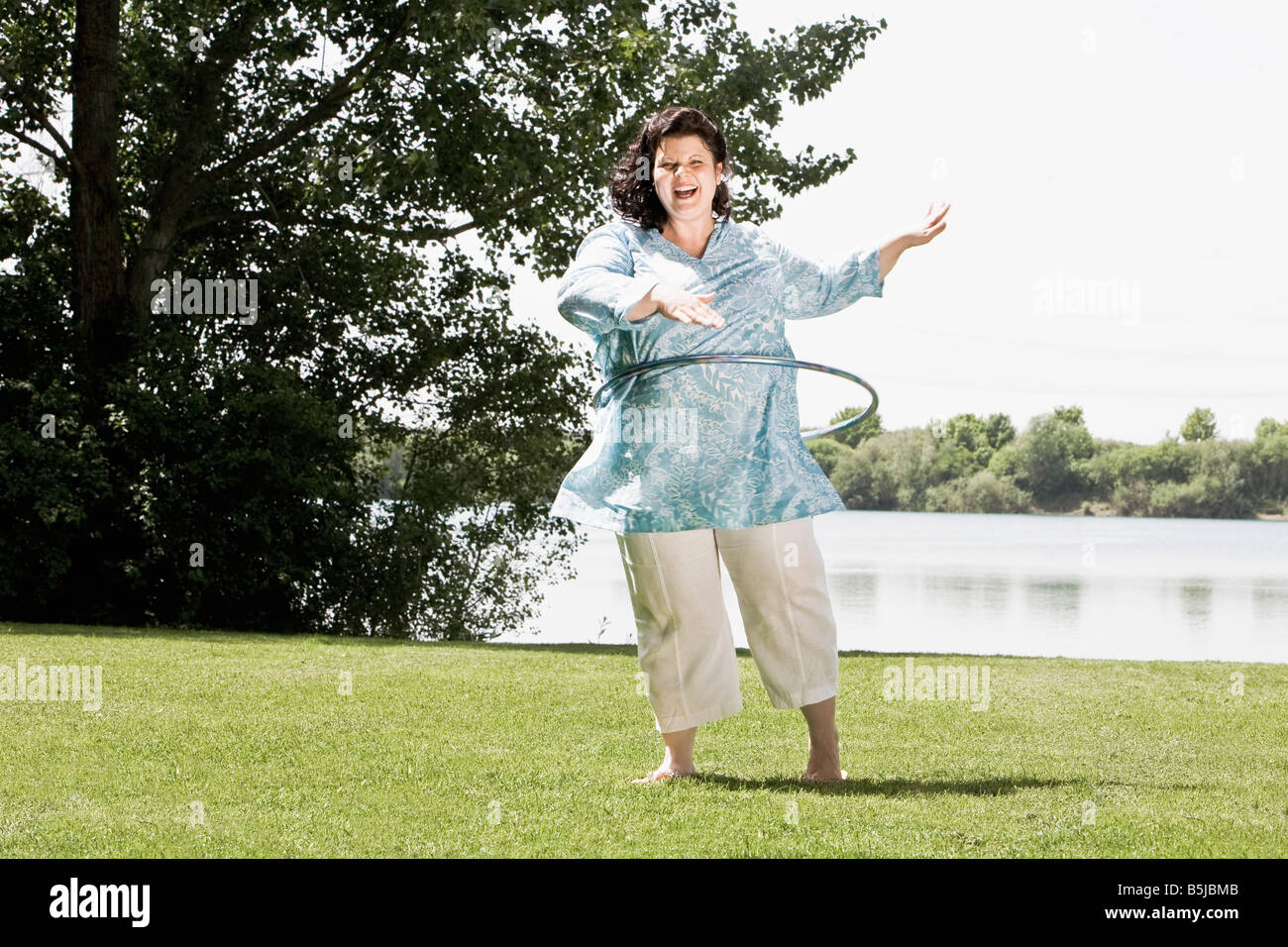 full body portrait of overweight woman doing hula hoop in the park ...