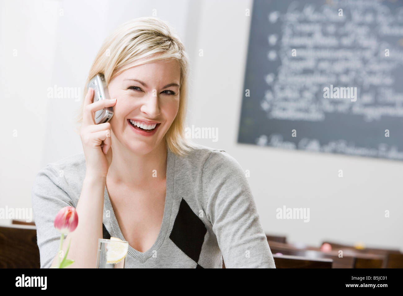 young woman sitting at restaurant table talking on mobile phone Stock ...