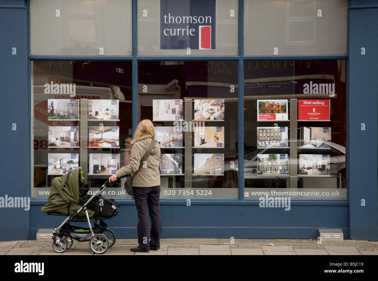 Woman with child in pushchair looking in estate agent s window Upper ...