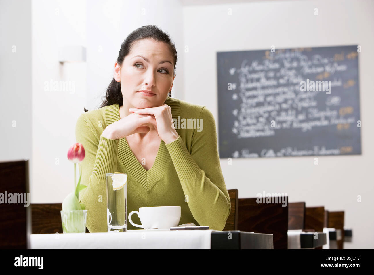 sad looking young woman sitting at restaurant table Stock Photo - Alamy