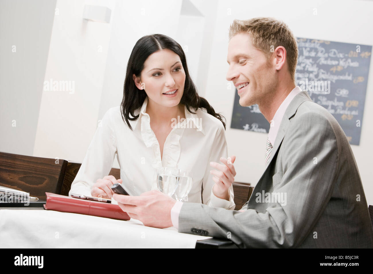 businesswoman and male colleague having conversation at restaurant ...