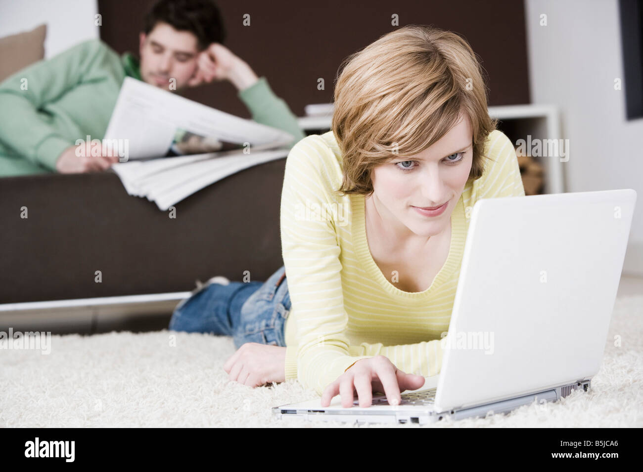 woman working with laptop computer at home while man is reading ...