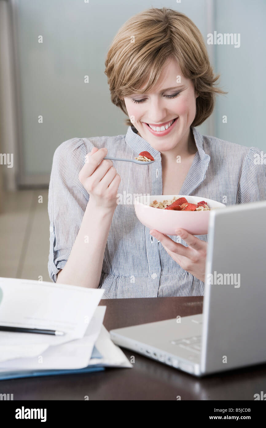 portrait of woman at home in front of computer eating snack Stock Photo ...