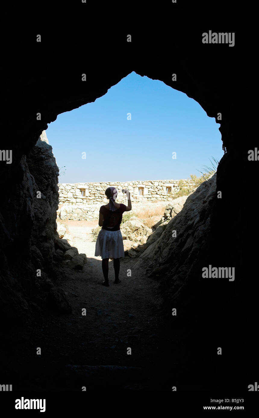 Woman standing inside cave in silhouette taking picture with digital ...