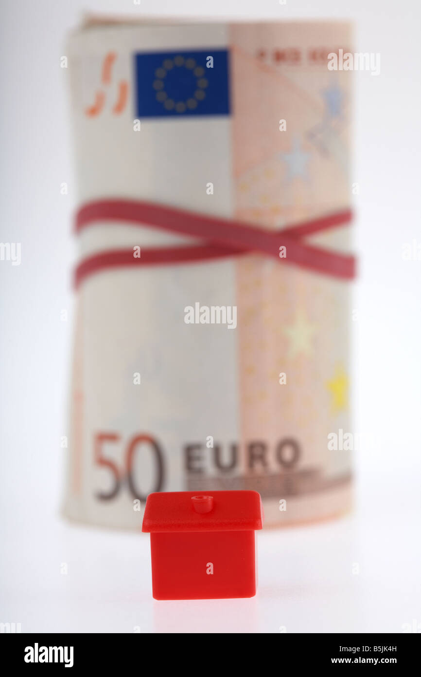 one red house on front of a wad of 50 euro bank notes cash tied up in a ...