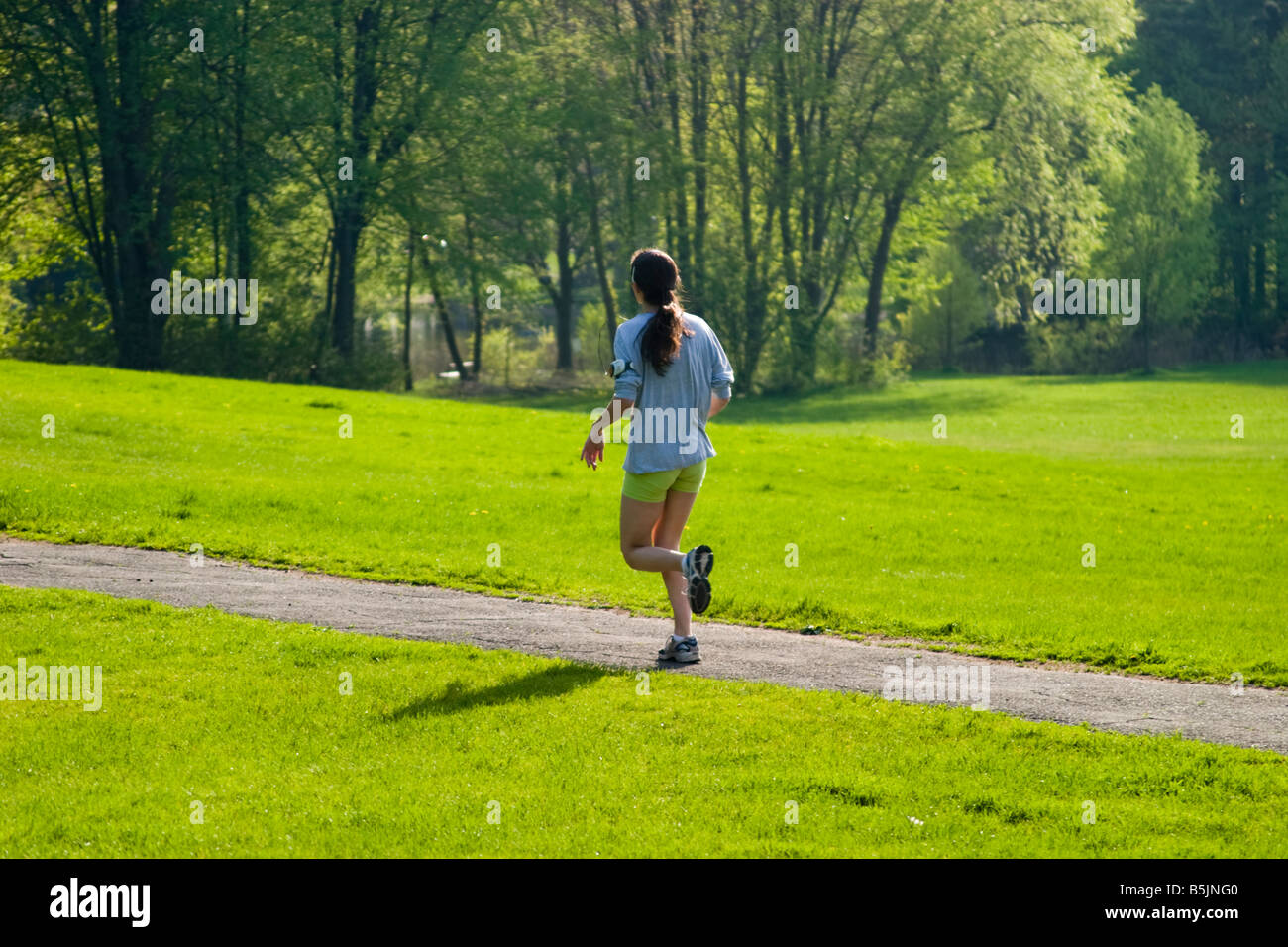 Young woman jogging down a path at a park Stock Photo - Alamy