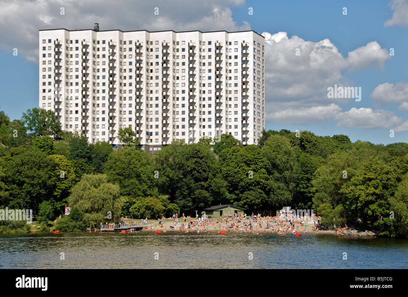 Crowded beach on a summers day with high rise apartment block ...