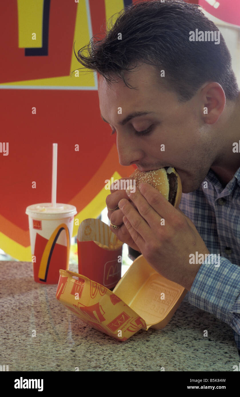 young man eating burger in fast food restaurant Stock Photo - Alamy