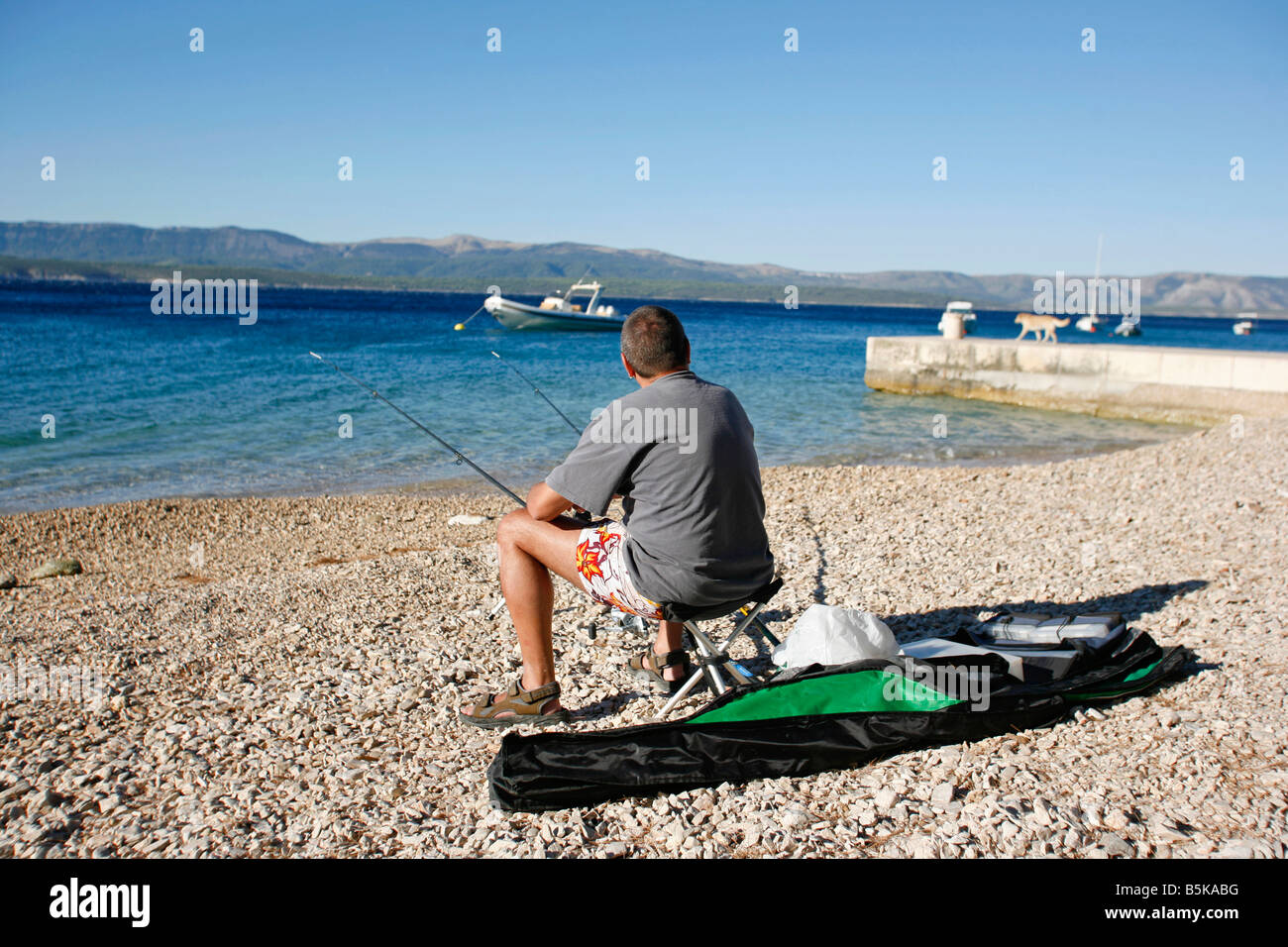 Fisherman on beach waiting for a catch Stock Photo - Alamy