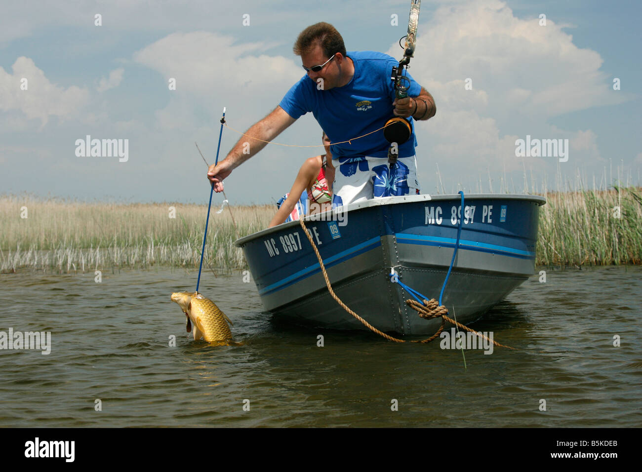 A bowfisherman lifting a fish out of the water after hitting it with an ...