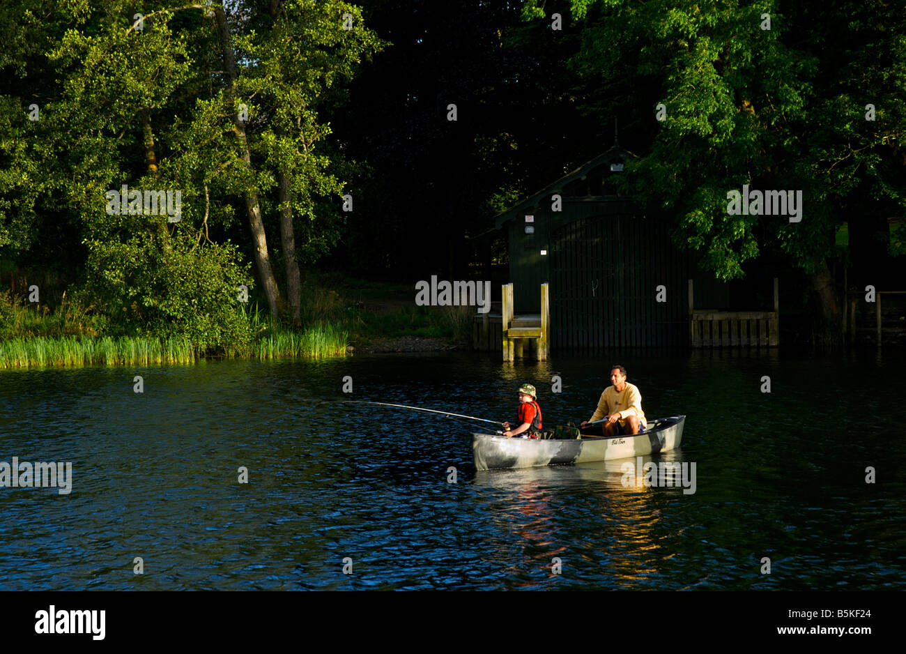 Man and boy fishing from dinghy, River Leven, draining out of Lake ...