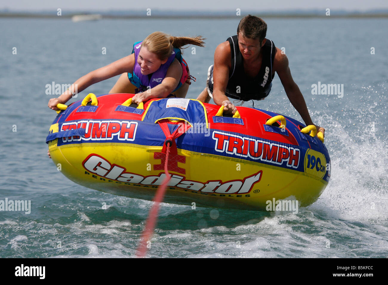Teenage boy and girl having a thrilling ride on an inflatable tube ...