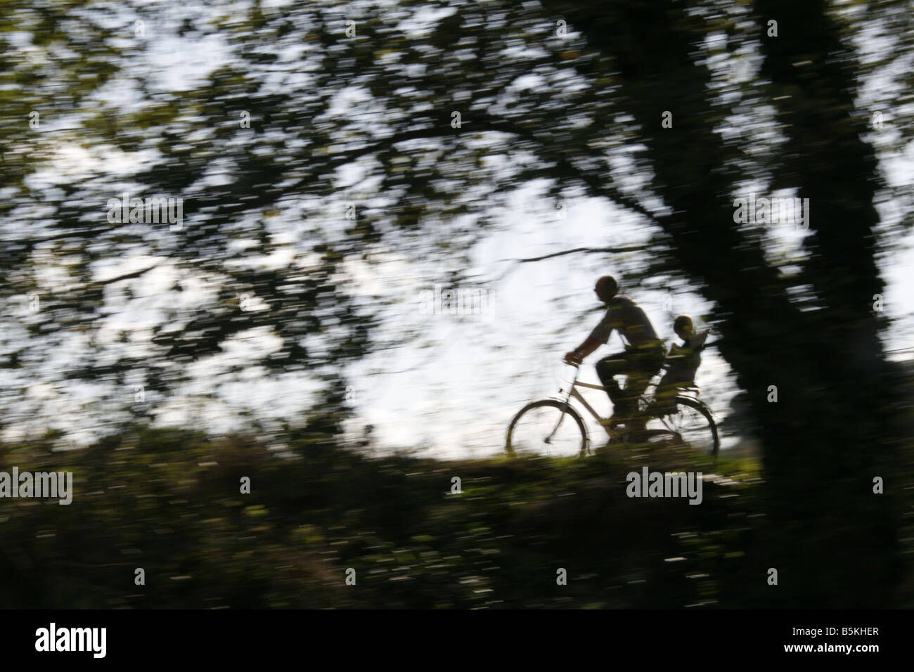 person and child riding fast bike on rural lane countryside Stock Photo ...