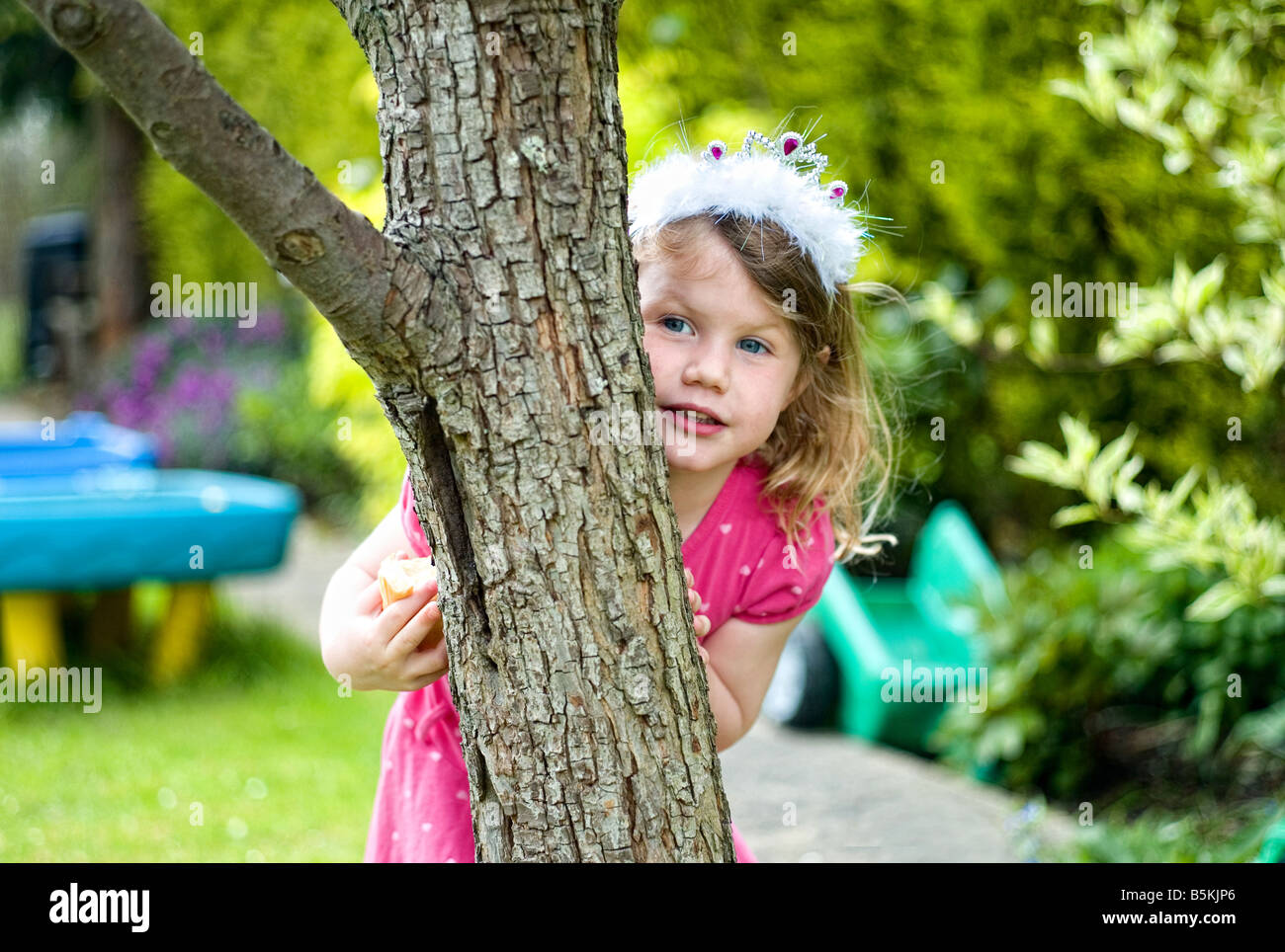 Girls hiding behind tree Stock Photo - Alamy