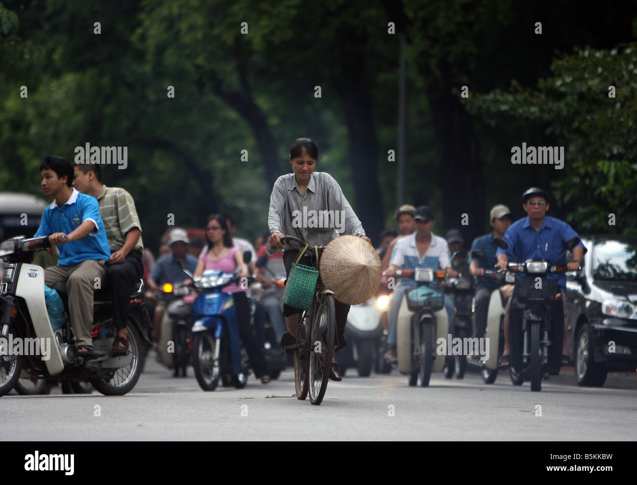 A lone bike rider navigates her way through traffic on a busy street in ...