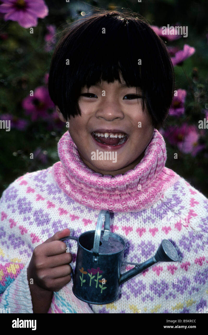Pretty little Chinese girl with a watering can Stock Photo - Alamy