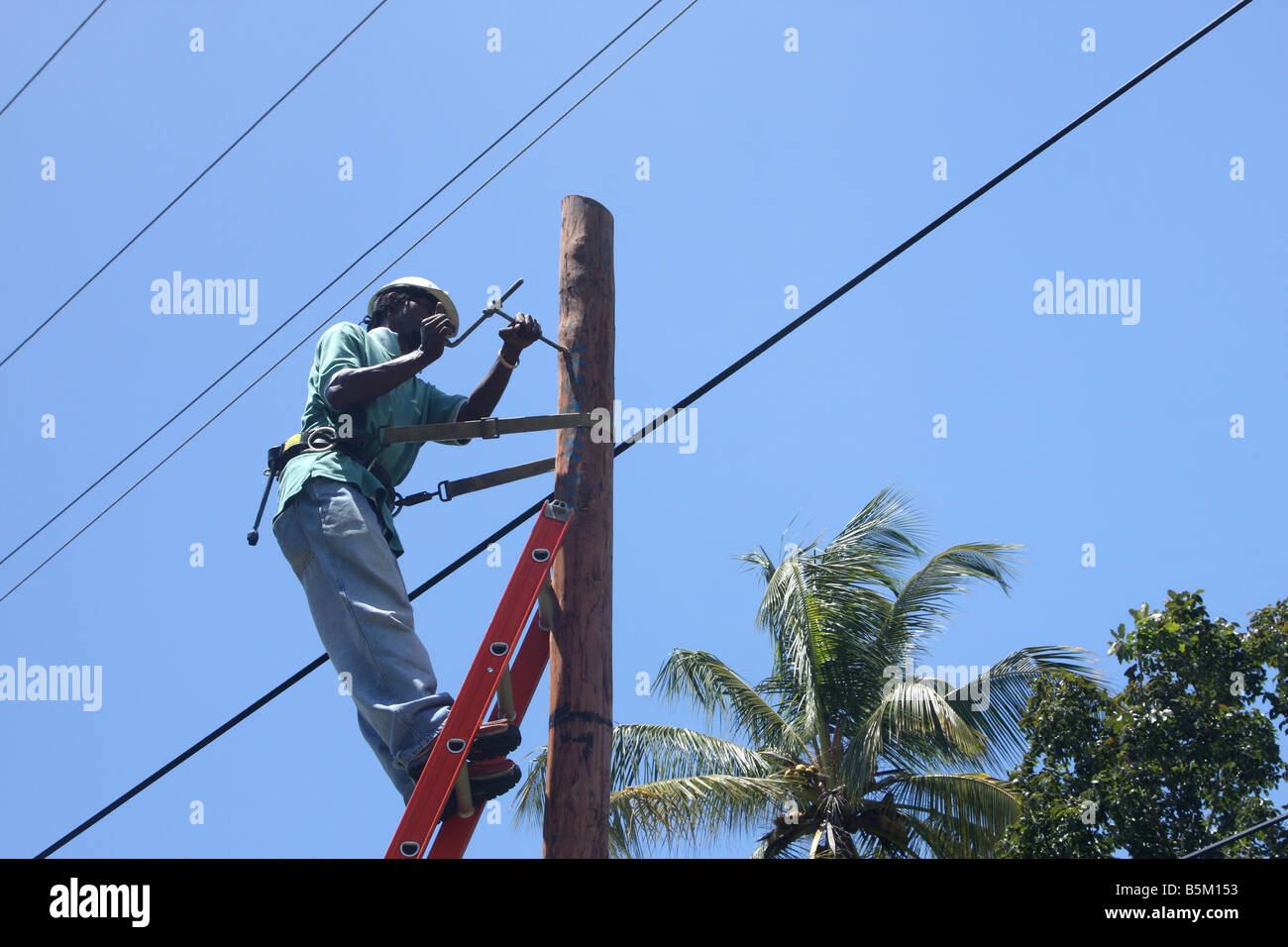 man with helmet working on a pole with electrical wire in Tobago Stock ...