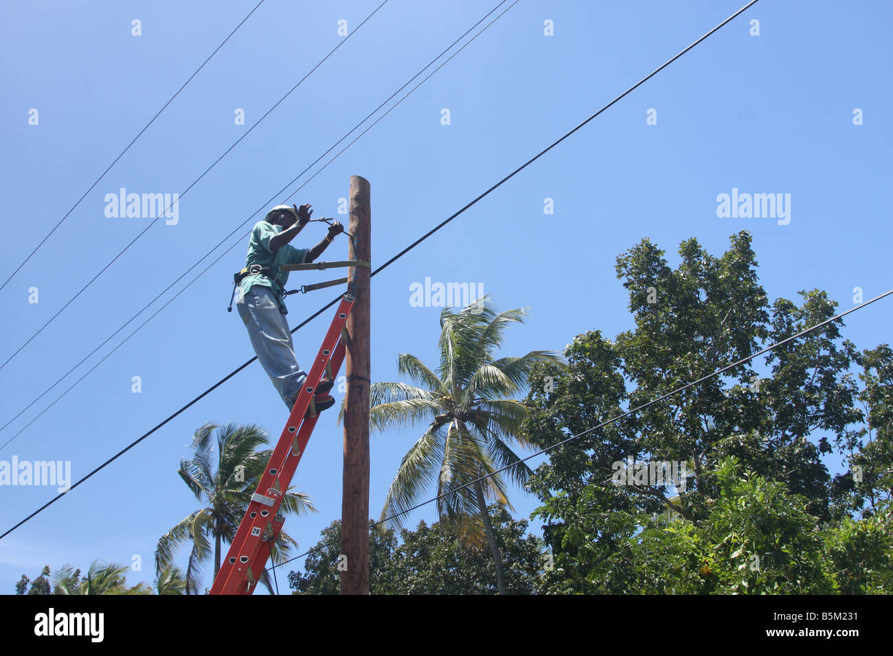 man with helmet working on a pole with electrical wire in Tobago Stock ...