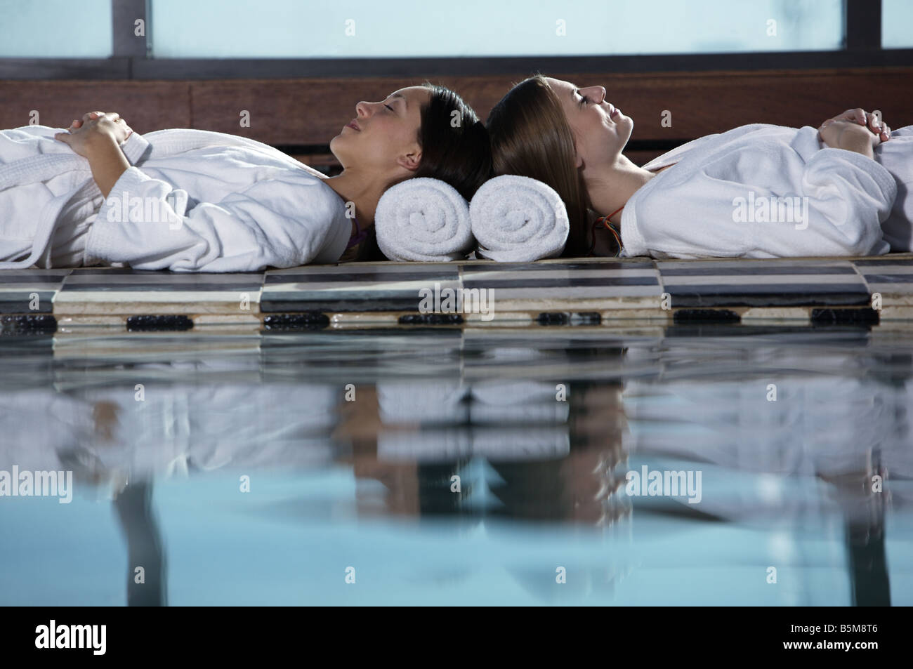 Two women laying by the pool Stock Photo - Alamy