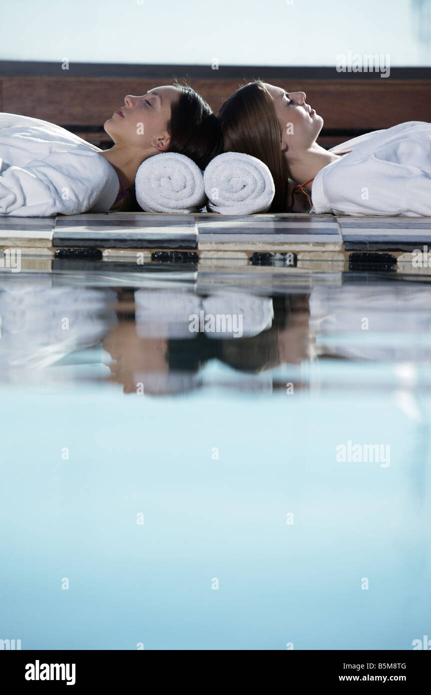 Two women laying by the pool Stock Photo - Alamy