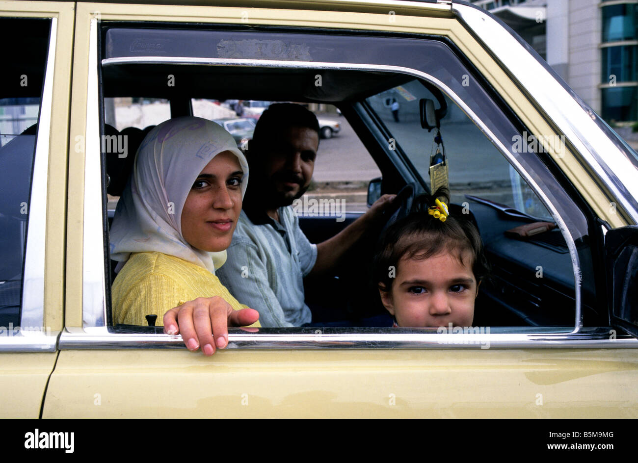 A young Muslim woman with her daughter share the front seat of a ...
