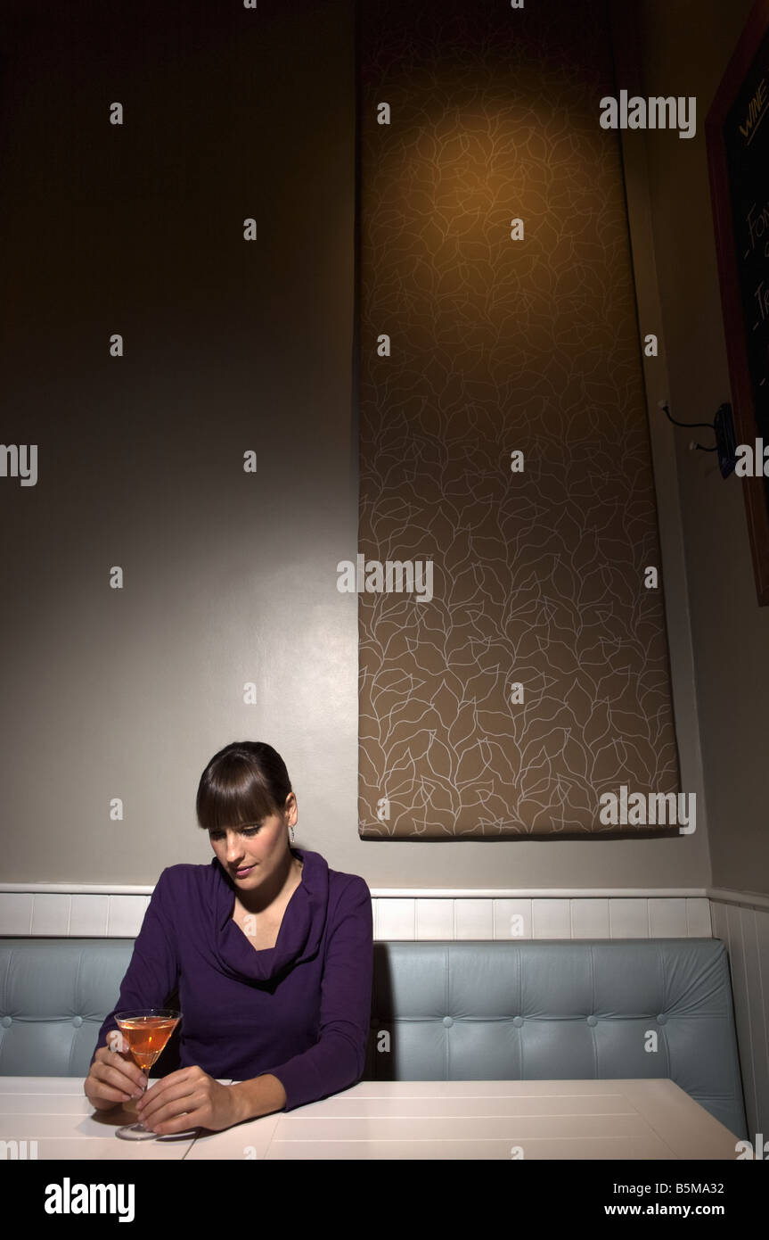 A woman sitting alone drinking a martini Stock Photo - Alamy