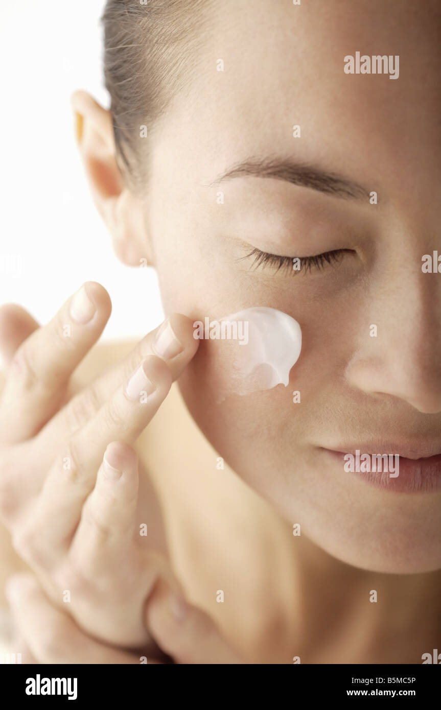 A woman rubbing lotion on her face Stock Photo - Alamy